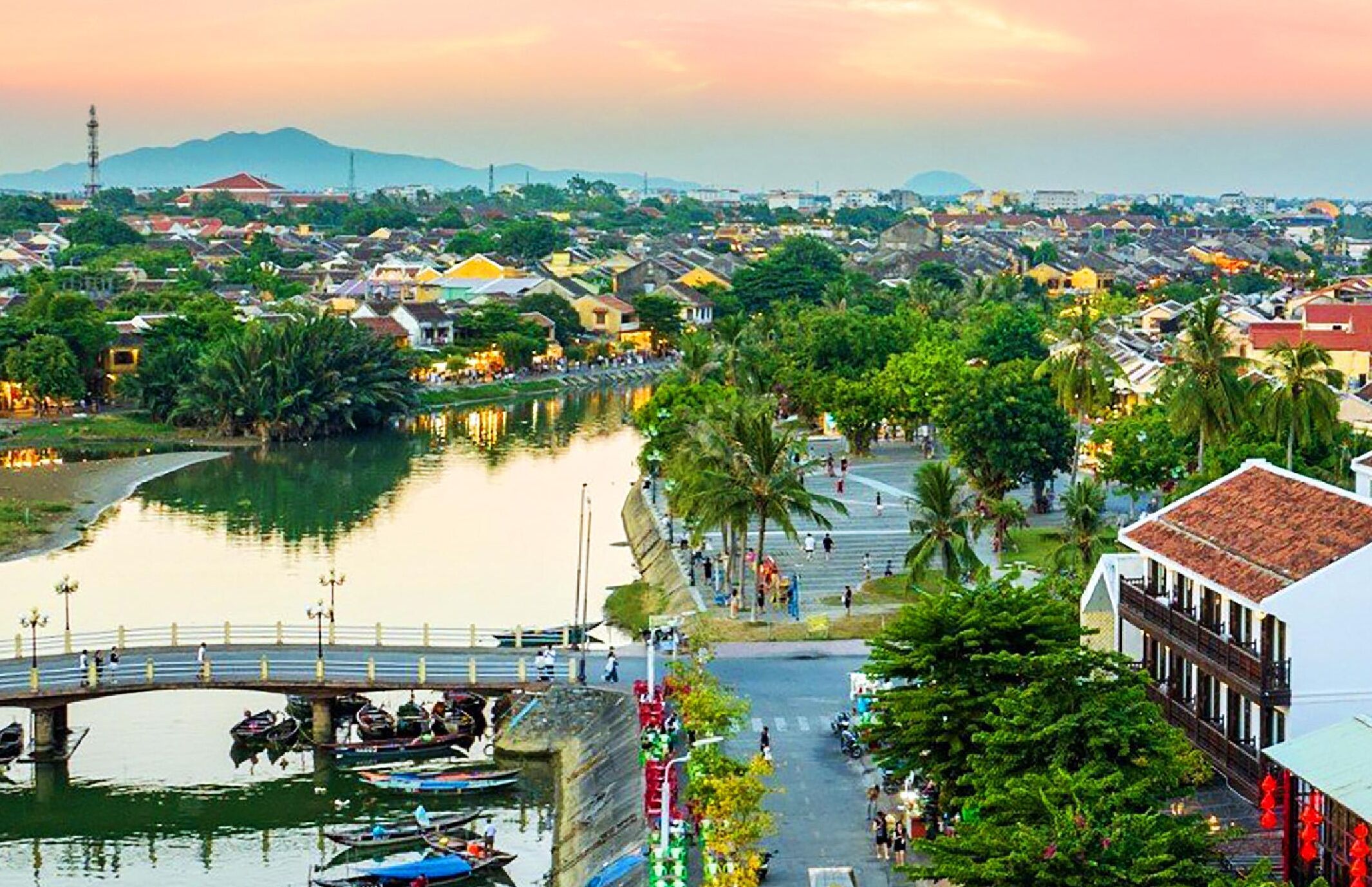 Uma cidade ribeirinha com uma ponte, barcos e edifícios ao longo da água.