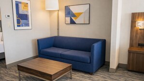 Quarto com um sofá azul, uma mesa de centro de madeira e duas obras de arte emolduradas na parede.