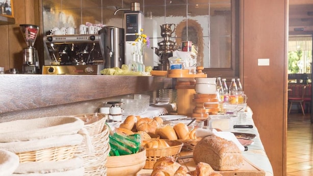 Buffet com diversos pães, doces e uma máquina de café.