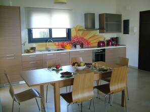 Cozinha moderna com armários de madeira, uma mesa de jantar com cadeiras e uma janela com vista.