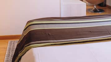 Quarto de hotel com cama, televisão na parede, escrivaninha e cadeira, e janela com cortinas.