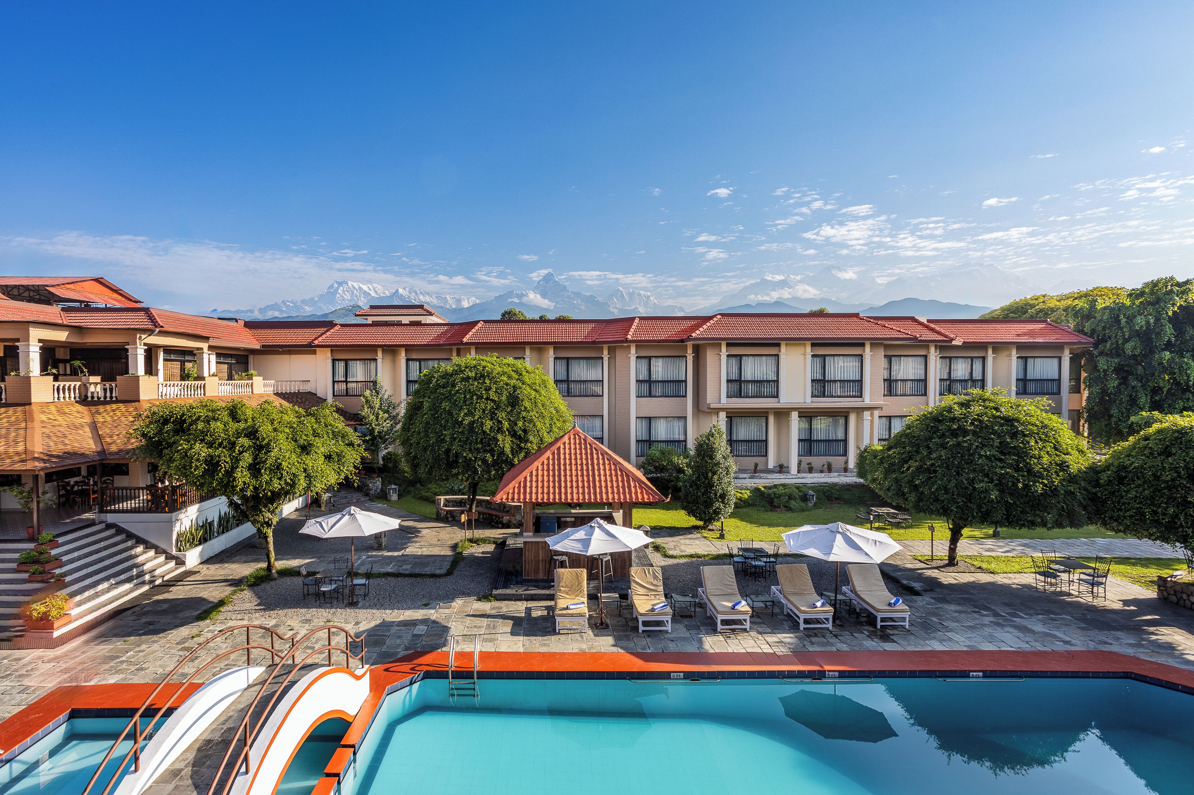 Um hotel com piscina, área de estar externa e vista para as montanhas.