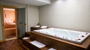 Um banheiro moderno com uma banheira grande, degraus de madeira e uma porta de madeira que dá para uma sauna.