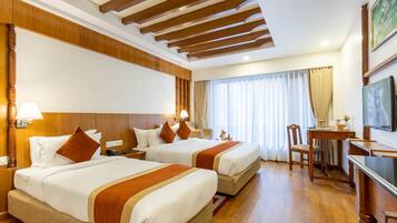 Quarto de hotel com duas camas, vigas de madeira no teto, uma escrivaninha, uma cadeira e uma televisão.