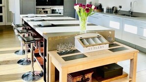 Uma cozinha moderna com ilha central, banquetes e um vaso de flores.