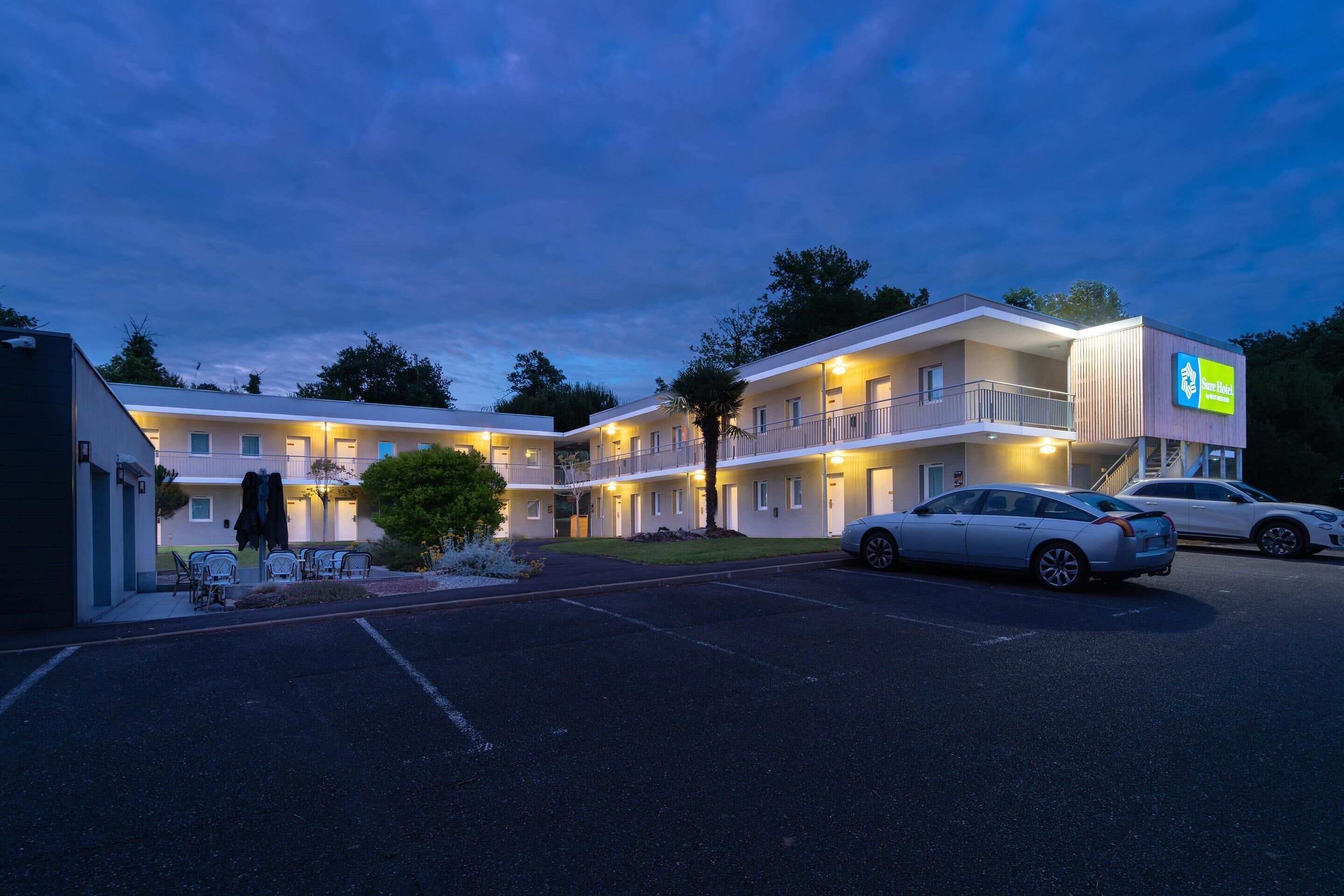 Um motel com várias divisões, estacionamento e placa indicando que aceita animais de estimação.