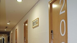 Corredor com portas de madeira numeradas 202, um quadro pendurado na parede e piso de madeira.