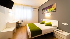 Quarto de hotel moderno com cama, mesa de cabeceira e escrivaninha.