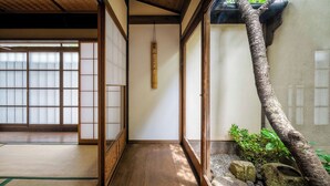 Um quarto japonês tradicional com tatames, portas deslizantes e um pequeno jardim de pedras.