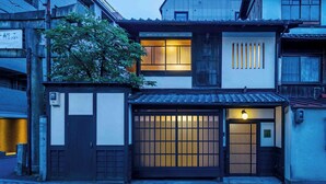 Uma casa japonesa tradicional com portão de correr, pequeno alpendre e entrada visível.