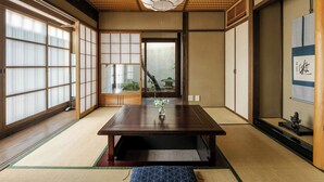 Um quarto japonês tradicional com tatames, uma mesa de madeira baixa, portas deslizantes e um lanterna de papel suspensa.