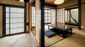 Um quarto japonês tradicional com tatames, portas deslizantes e uma mesa baixa com almofadas.