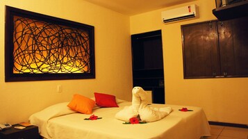 Quarto de hotel com cama, um objeto decorativo na parede, um aparelho de ar condicionado e um armário de madeira.