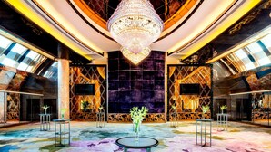 Um hall espaçoso com um grande candelabro, colunas de mármore e um design de piso colorido.