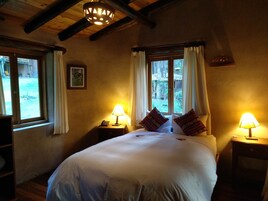 Quarto com cama grande, duas luminárias de cabeceira, telefone e janela com cortinas.