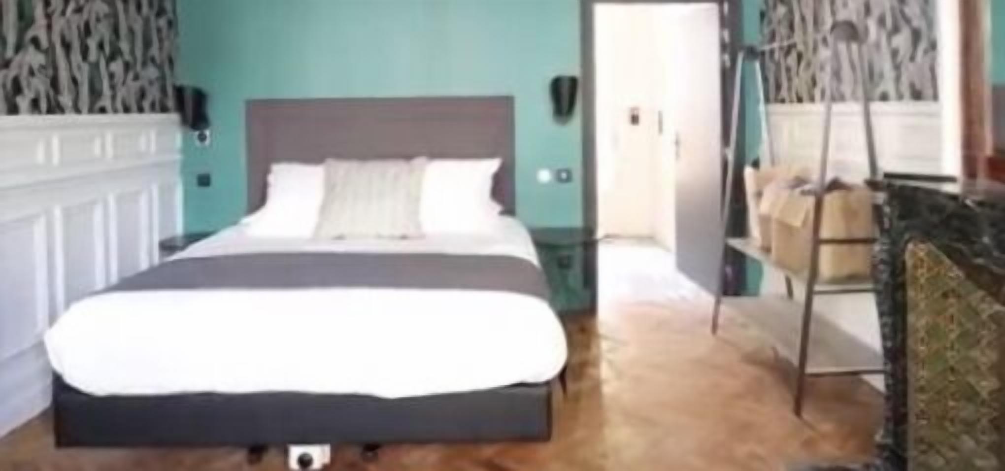 Quarto com uma cama grande, um guarda-roupa e um espelho.