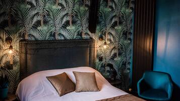 Quarto com cama, cabeceira, luminária na parede, cadeira e carpete estampado.