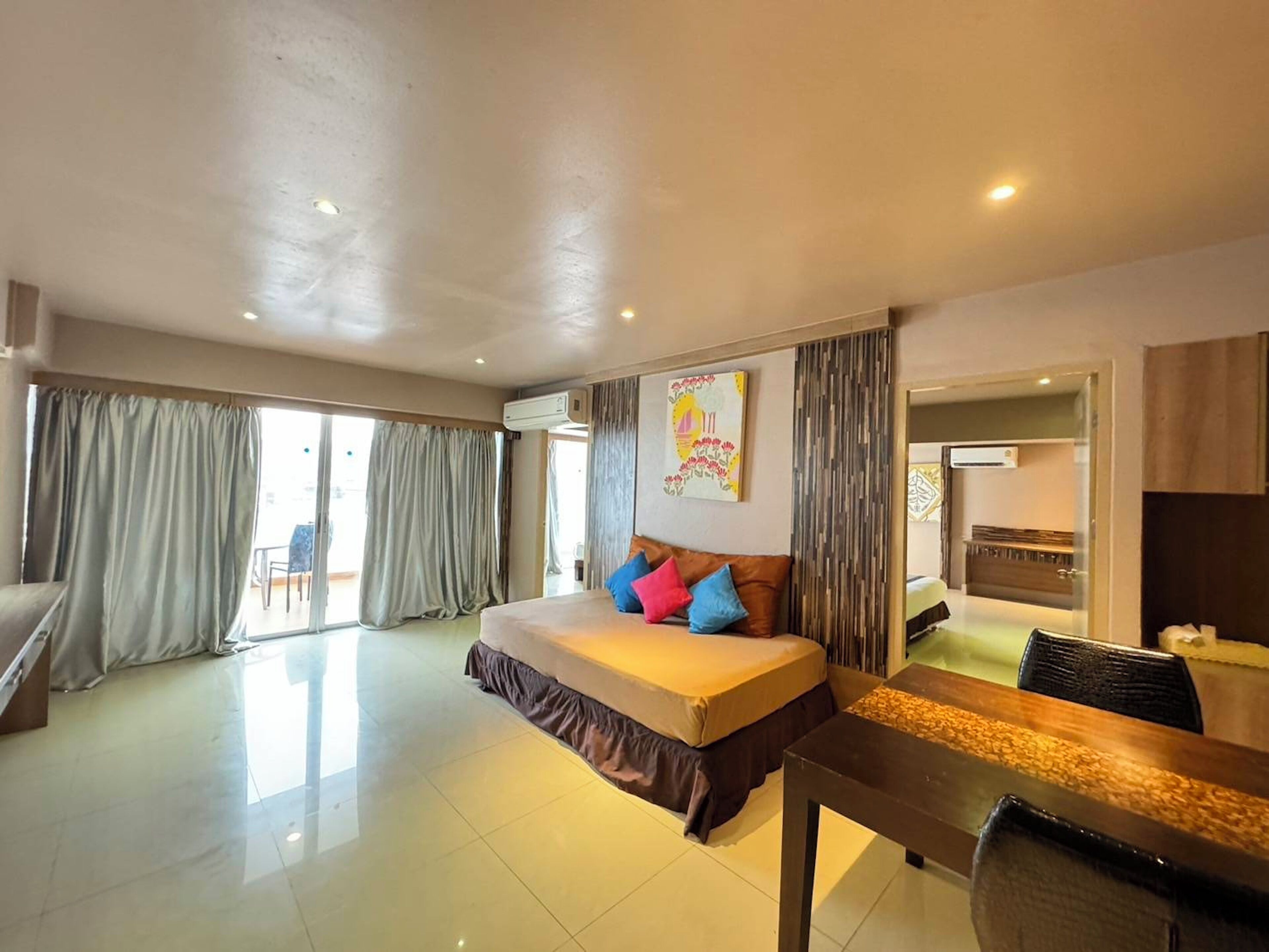 Quarto de hotel espaçoso com uma cama grande, uma mesa de jantar e uma cozinha compacta.