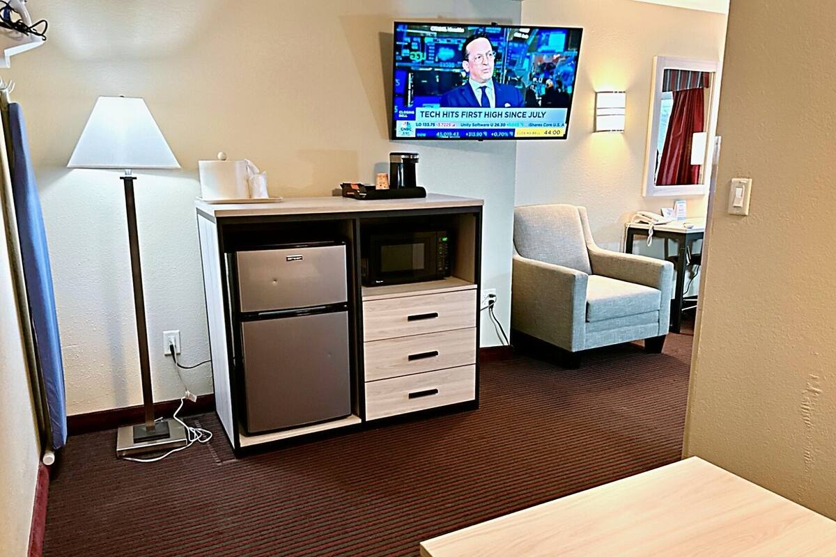 Quarto de hotel com escrivaninha, cadeira, televisão e minibar.
