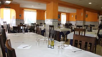 Um restaurante com várias mesas e cadeiras, e um letreiro 'SALIDA' indicando uma saída.