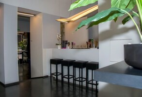 Uma área de bar moderna com banquetas pretas, uma planta em vaso e um quadro de cardápio.