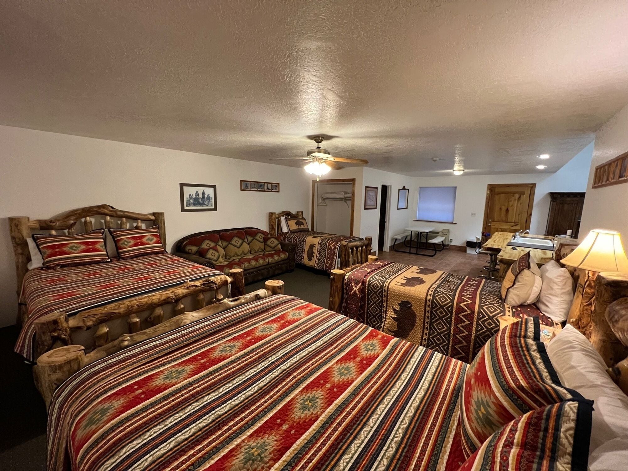 Quarto com três camas, uma mesa de jantar e uma pia.