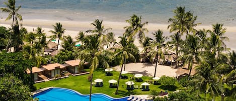 Um resort com piscina, praia e palmeiras.