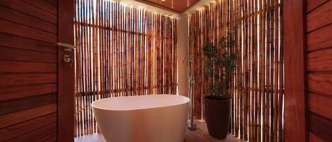 Um banheiro moderno com uma banheira de imersão, painéis de parede de bambu e um vaso de planta.