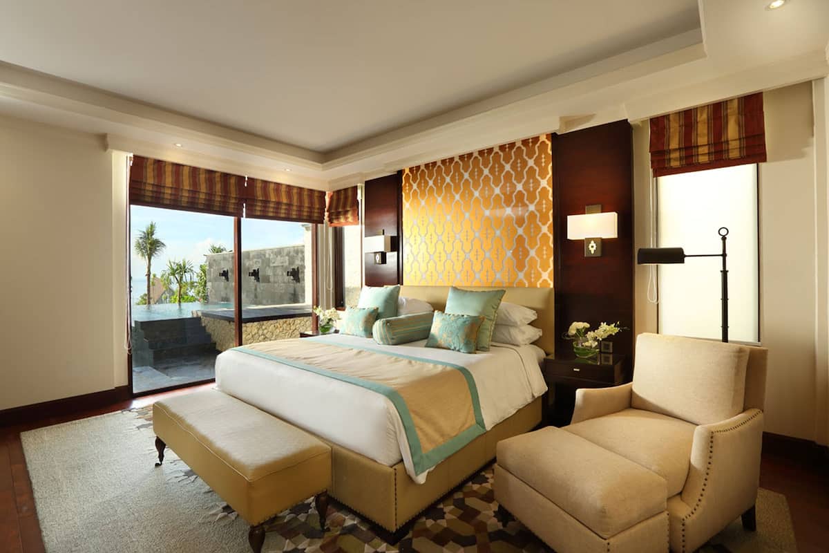 Quarto de hotel com cama grande, área de estar, varanda com vista e janela ampla com vista.