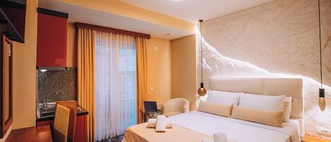 Quarto de hotel com uma cama, uma escrivaninha, uma cadeira e um laptop.