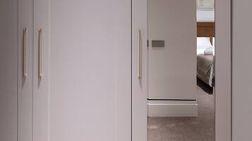Quarto com um guarda-roupa branco grande e de duas portas, e um espelho.