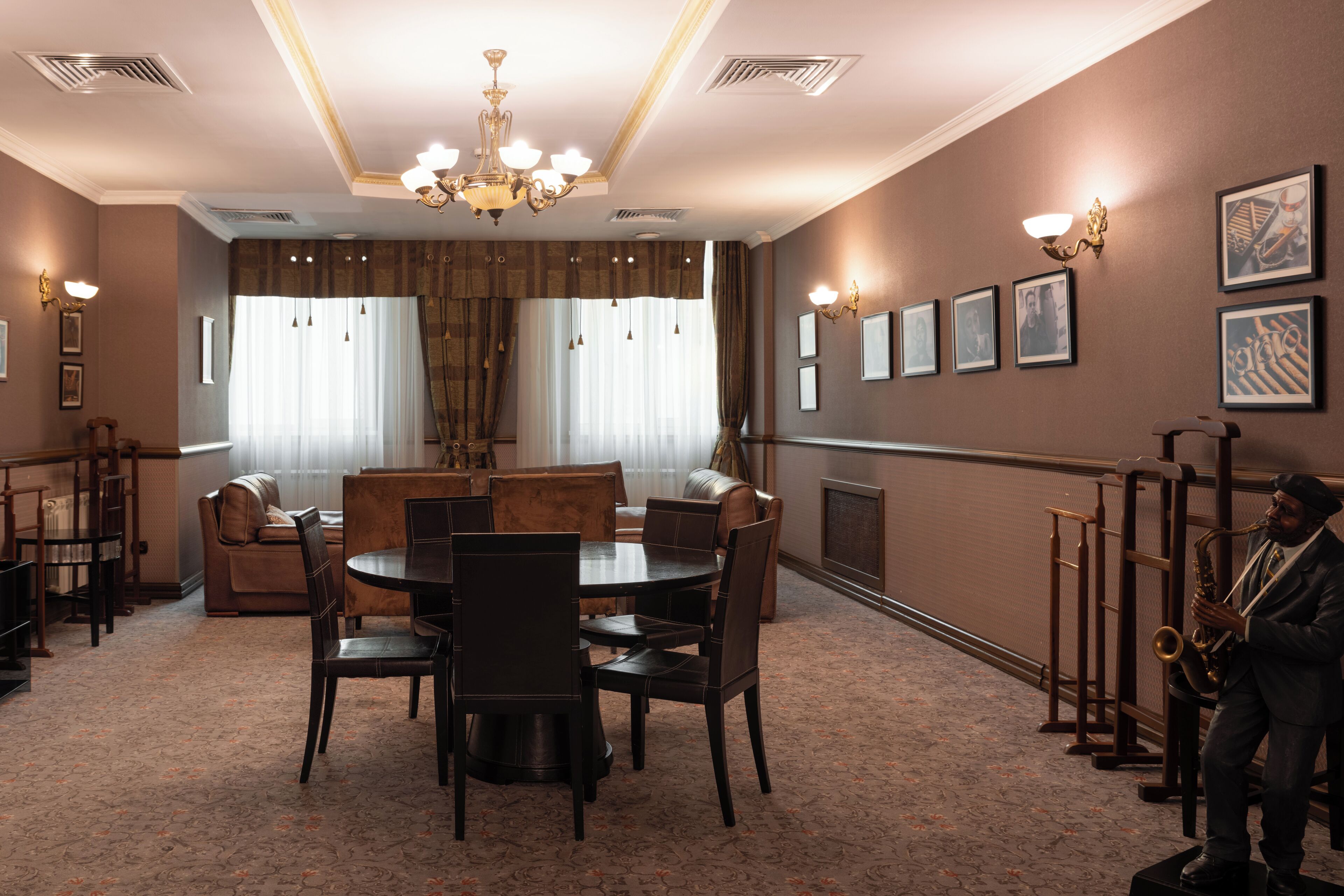 Uma sala de jantar formal com uma mesa redonda, cadeiras e um candelabro.