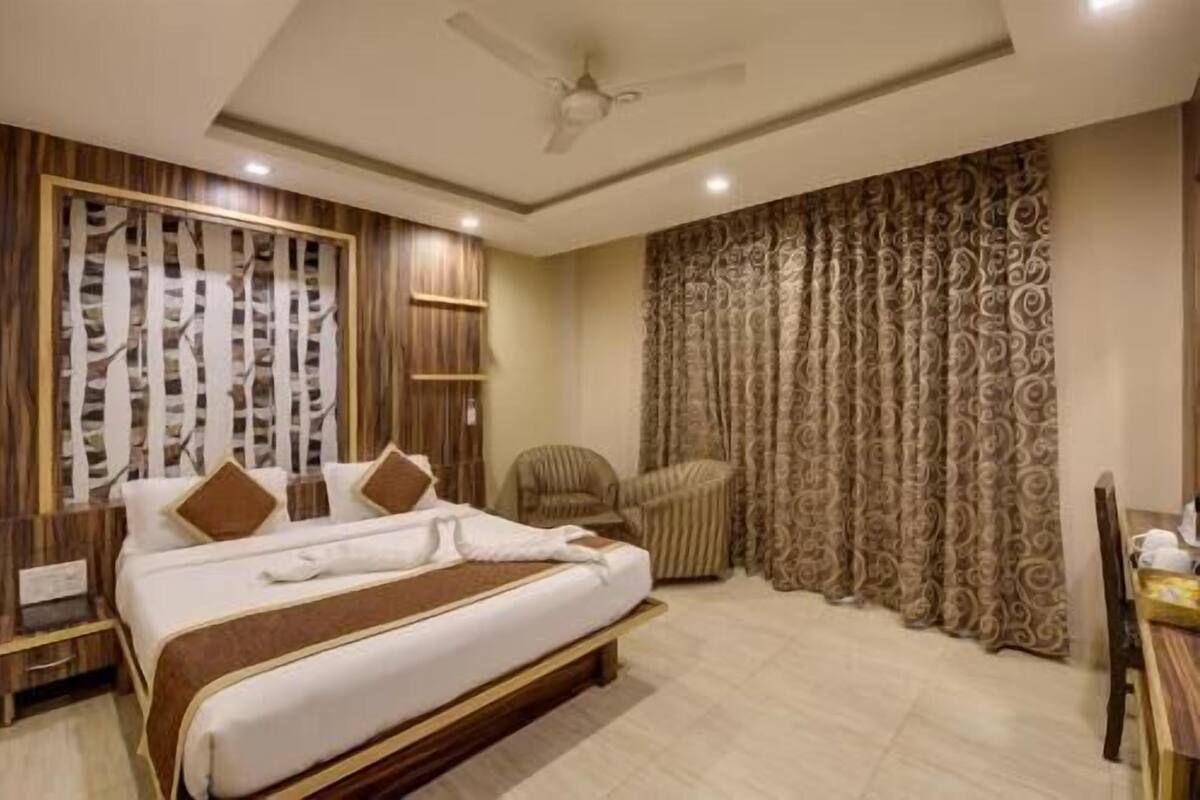 Quarto com cama, cadeira, escrivaninha e cortinas.