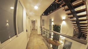 Interior moderno com escada em espiral, guarda-corpo de vidro e vista para o andar inferior.