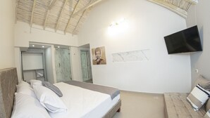 Um quarto com uma cama, televisão, sofá e obras de arte nas paredes.
