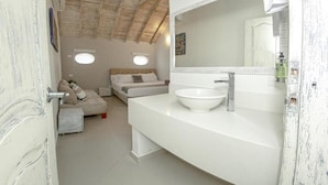 Casa de banho moderna com uma grande pia branca, um espelho e um ventilador de teto.