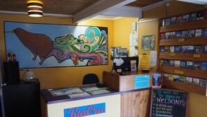 Uma mesa de recepção com um mapa, um grande mural colorido e uma estante com livros de viagem.