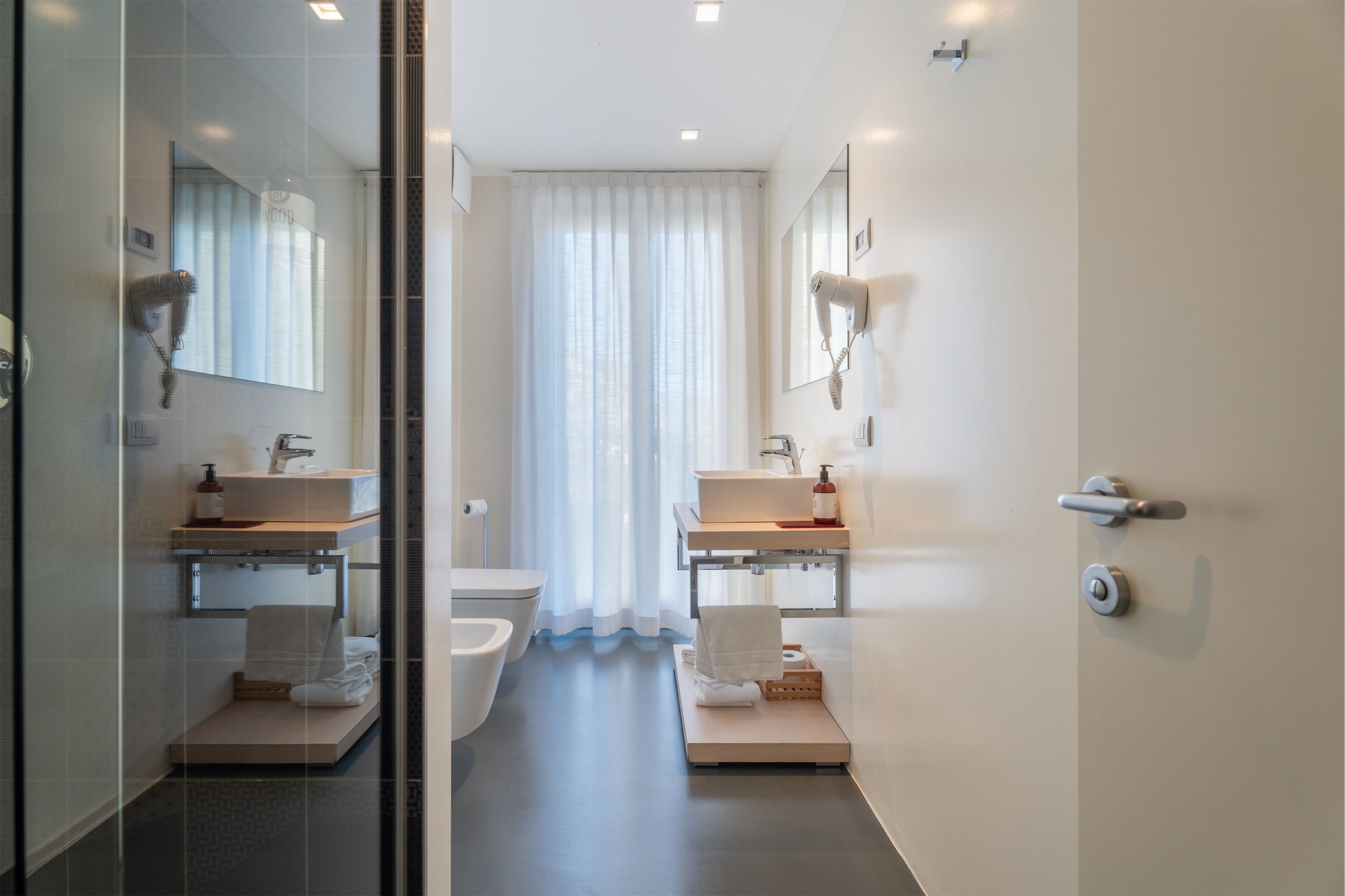 Uma casa de banho moderna com duas pias, sanita e zona de duche.