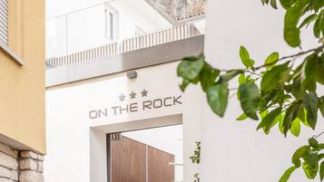 Entrada de hotel com uma placa que diz 'ON THE ROCK'.