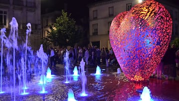 Um espetáculo noturno de fontes com múltiplos jatos de água e uma grande escultura iluminada em formato de coração.