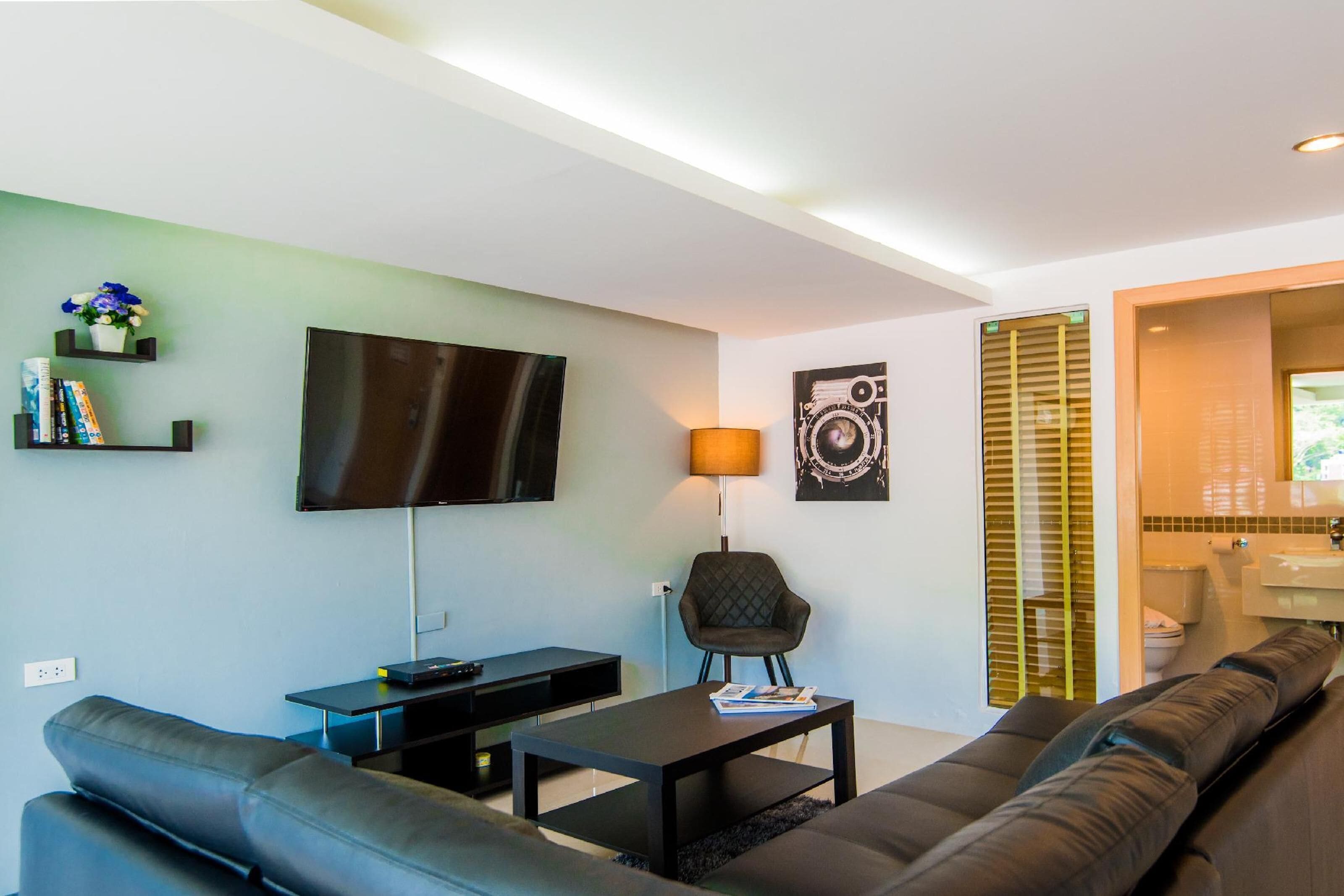 Uma sala de estar moderna com uma TV de tela plana, um sofá, uma mesa de centro e um abajur.