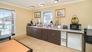 Uma cozinha com bancada, armários, micro-ondas e pia.