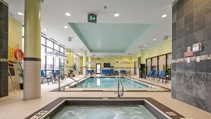 Piscina interior com piso ladrilhado, hidromassagem e cadeiras de descanso.
