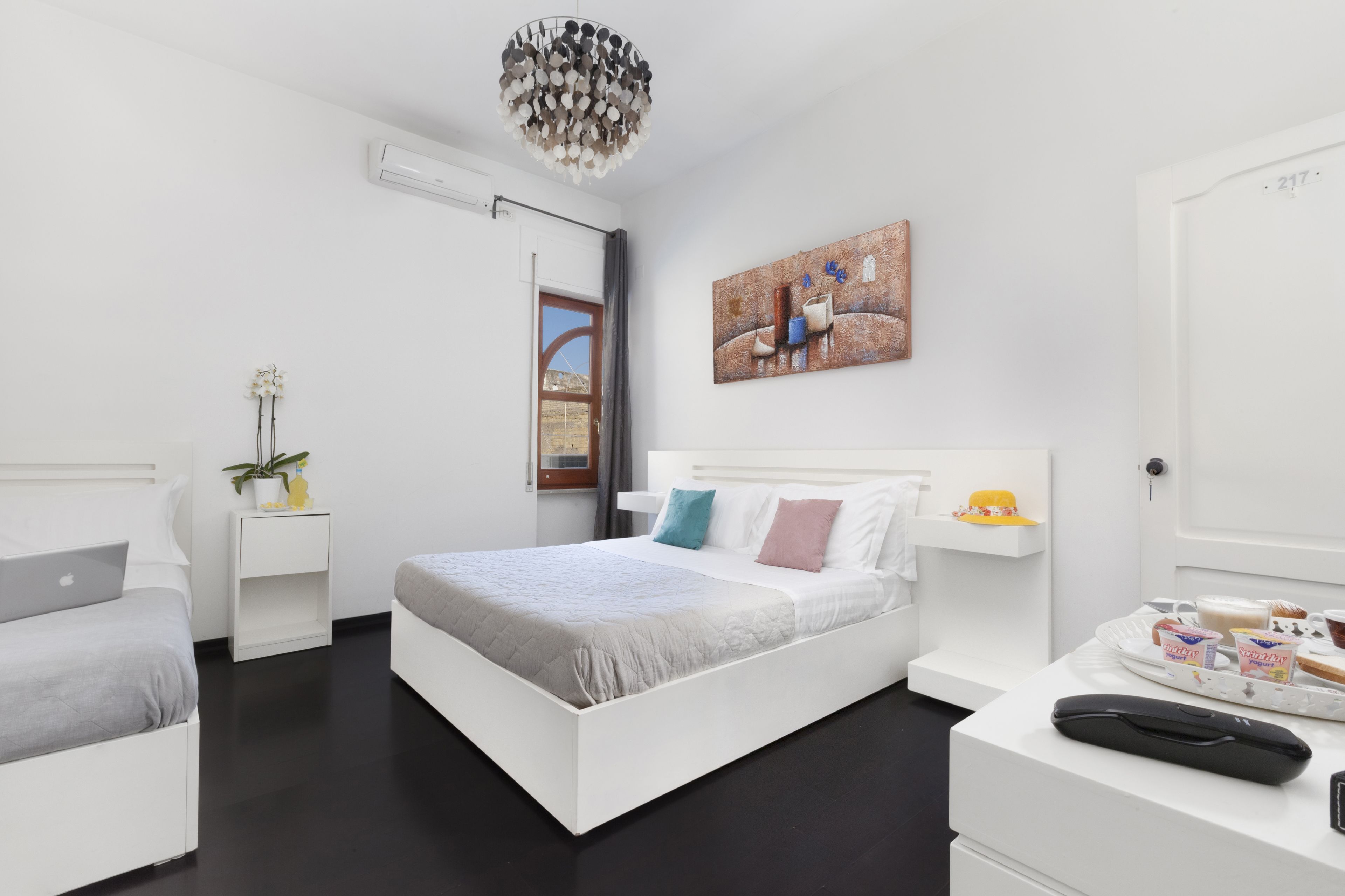 Um quarto moderno com cama, mesas de cabeceira, escrivaninha e um quadro na parede.
