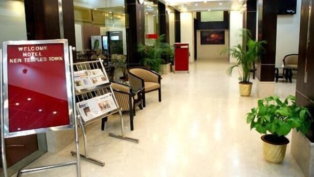 Um saguão de hotel com balcão de recepção, área de estar e placa de boas-vindas.