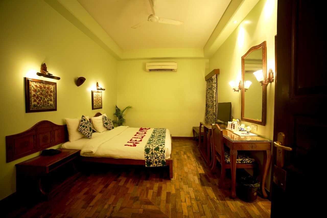 Quarto de hotel com cama, mesa de cabeceira, espelho, toucador e aparelho de ar condicionado.