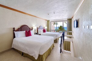Quarto de hotel com duas camas, televisão e varanda com vista para o oceano.