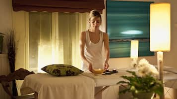Um quarto com uma cama, uma mesa com velas e um quadro na parede.