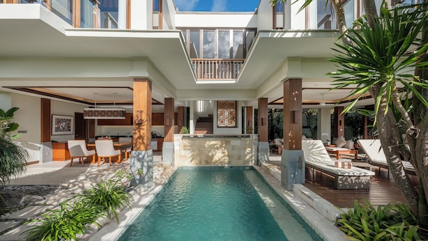 Uma área de piscina moderna, com vista clara para a piscina, espreguiçadeiras e um espaço de refeições com mesas e cadeiras.