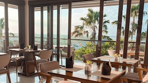 Uma sala de jantar moderna com grandes janelas, mesas de madeira e cadeiras confortáveis.